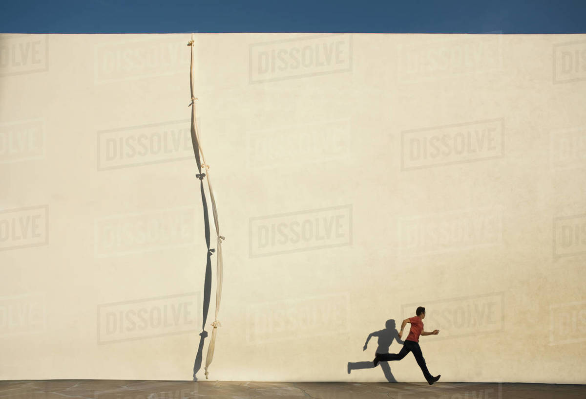 Man escaping by climbing rope over wall - Stock Photo - Dissolve