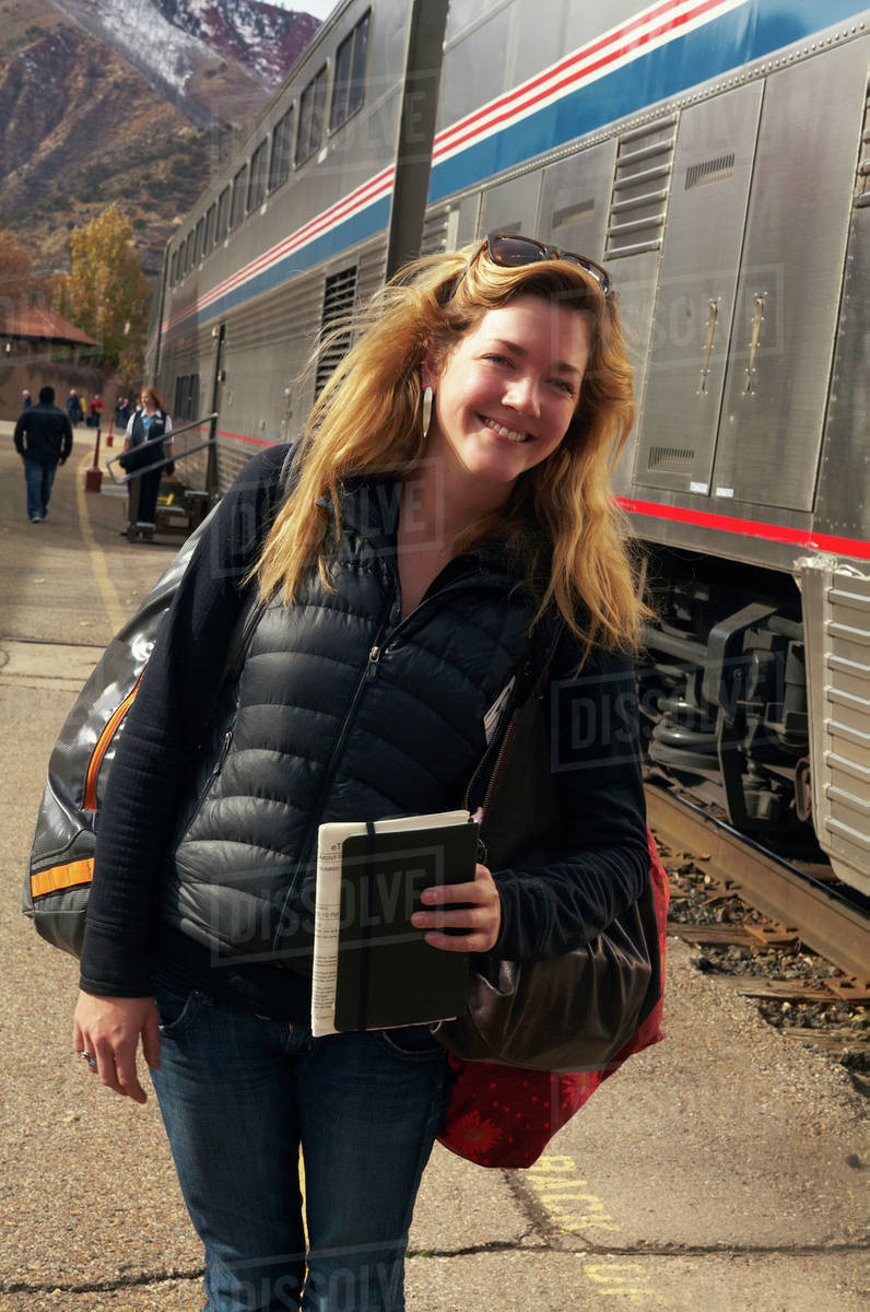 Woman smiling at train station - Stock Photo - Dissolve