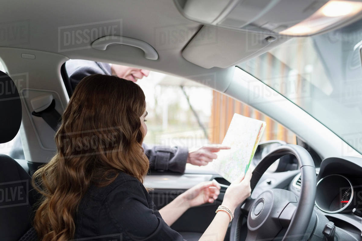 Man giving directions to young woman in car - Stock Photo - Dissolve