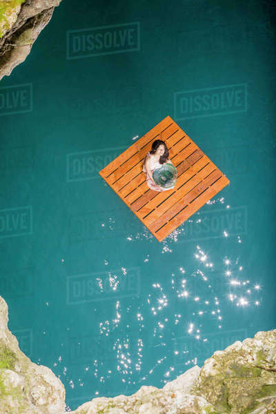 Aerial view of woman sitting on wooden raft - Royalty-free Stock Photo ...