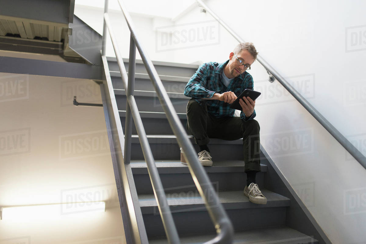 Man sitting on steps using tablet pc - Stock Photo - Dissolve