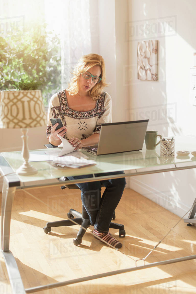 Woman sitting at desk using laptop - Royalty-free Stock Photo | Dissolve