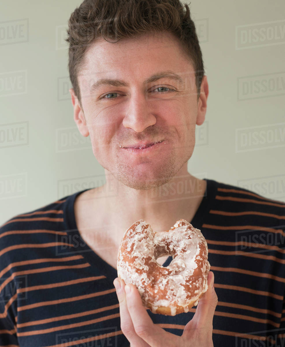 Portrait of man eating donut - Royalty-free Stock Photo | Dissolve