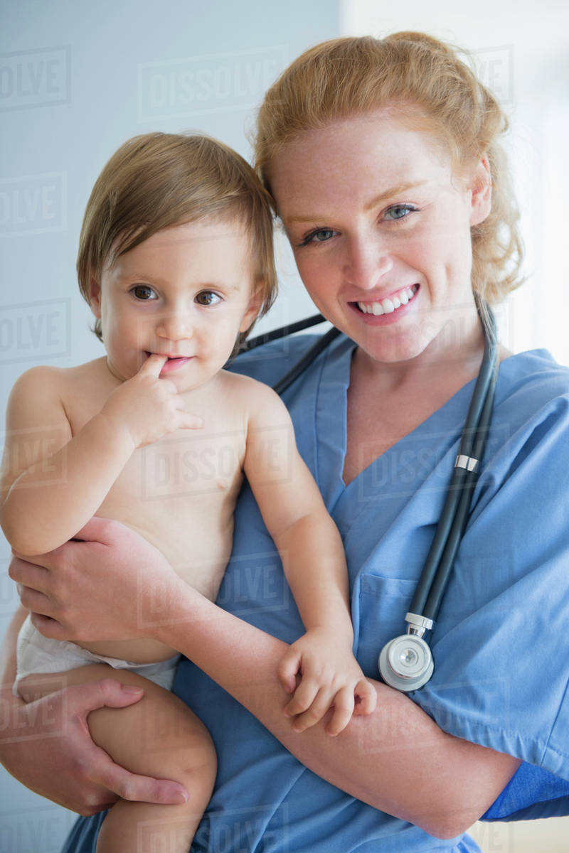 Portrait of female nurse carrying baby boy (12-17 months) - Royalty ...