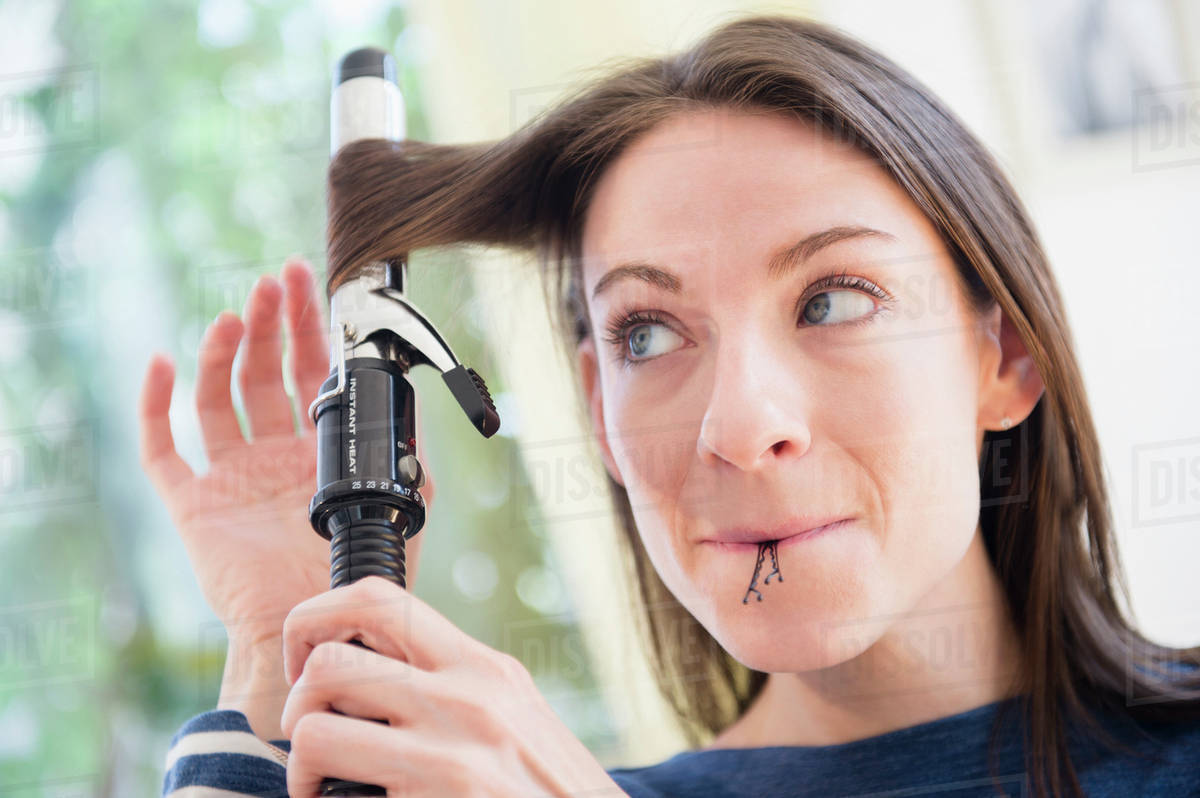 Woman using curler to do her hair - Royalty-free Stock Photo | Dissolve