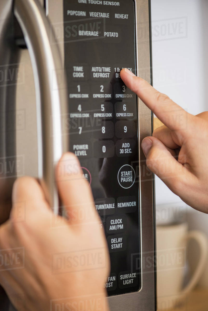 Close-up of hand using microwave oven - Royalty-free Stock Photo | Dissolve