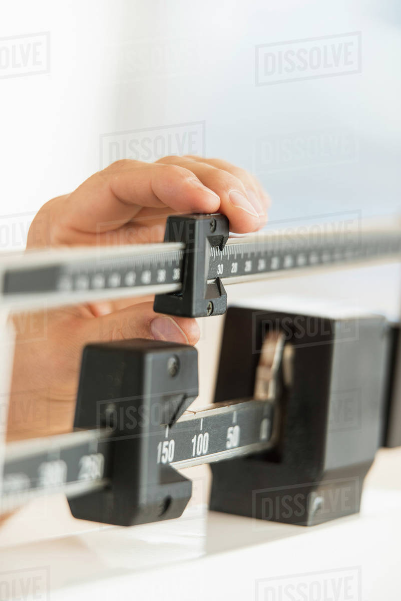 Hand adjusting weight scales - Royalty-free Stock Photo | Dissolve