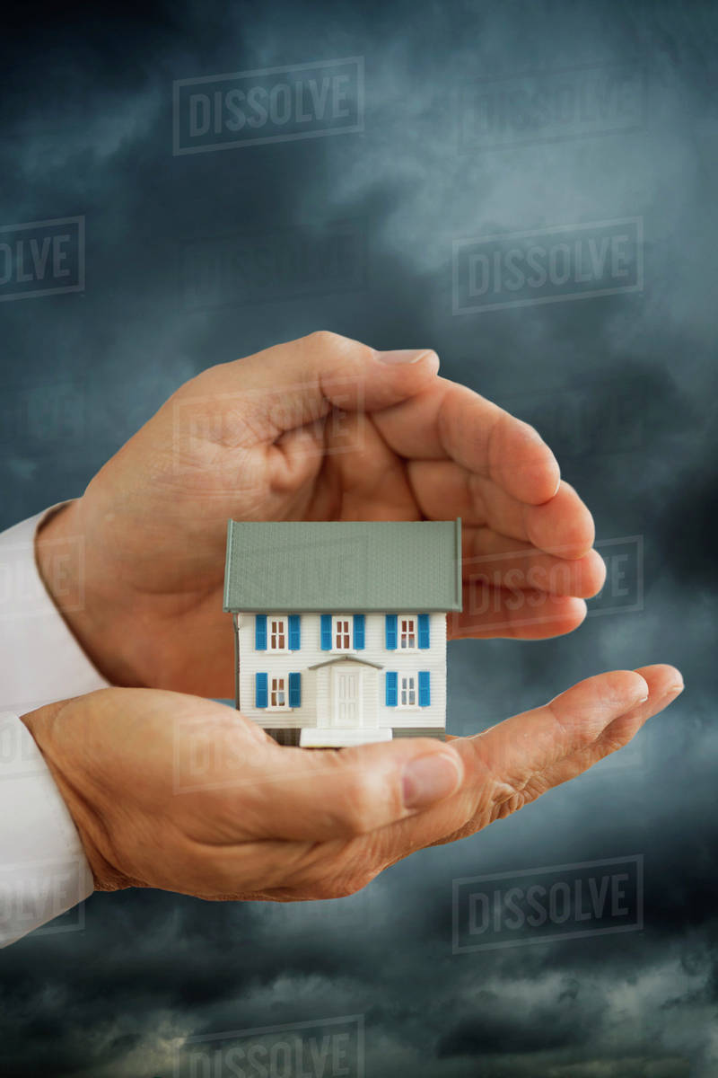 Hands holding model house in front of stormy sky - Royalty-free Stock ...