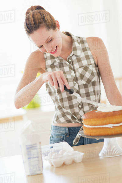 Woman decorating cake in kitchen - Stock Photo - Dissolve