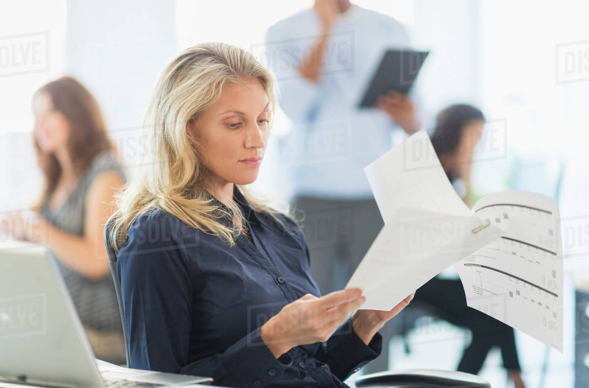 Woman reading at desk in office - Royalty-free Stock Photo | Dissolve