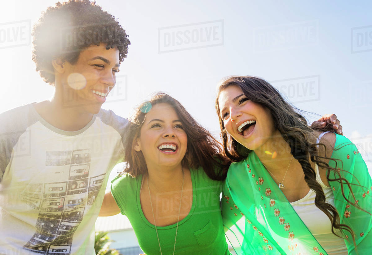 Group of friends (14-15) embracing and laughing - Stock Photo - Dissolve