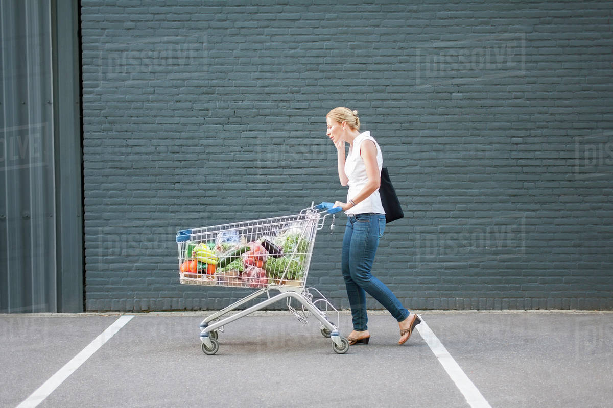 Woman walking with shopping cart - Royalty-free Stock Photo | Dissolve