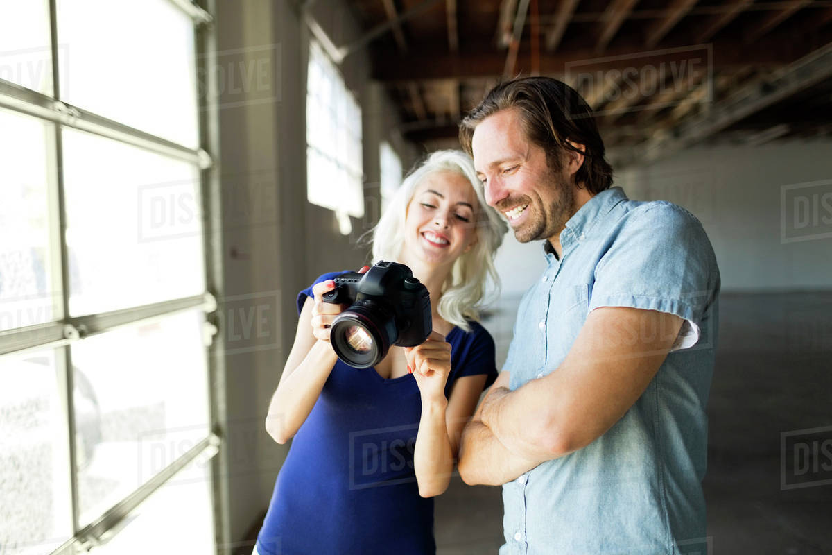 Woman and man looking at pictures in digital camera - Royalty-free ...