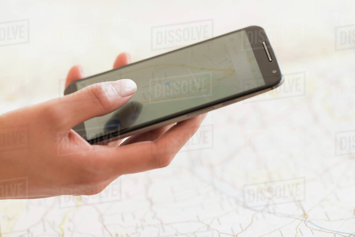 Hand holding smart phone, map in background - Stock Photo - Dissolve