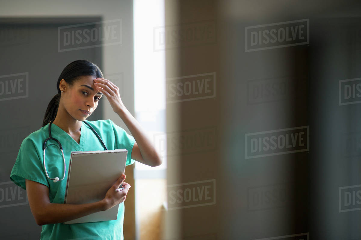 Female nurse with head in hands - Stock Photo - Dissolve
