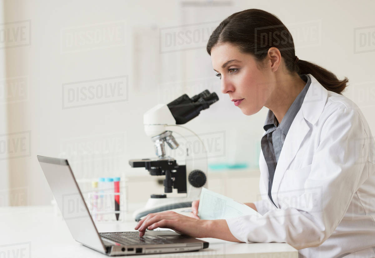 Scientist looking through microscope - Royalty-free Stock Photo | Dissolve