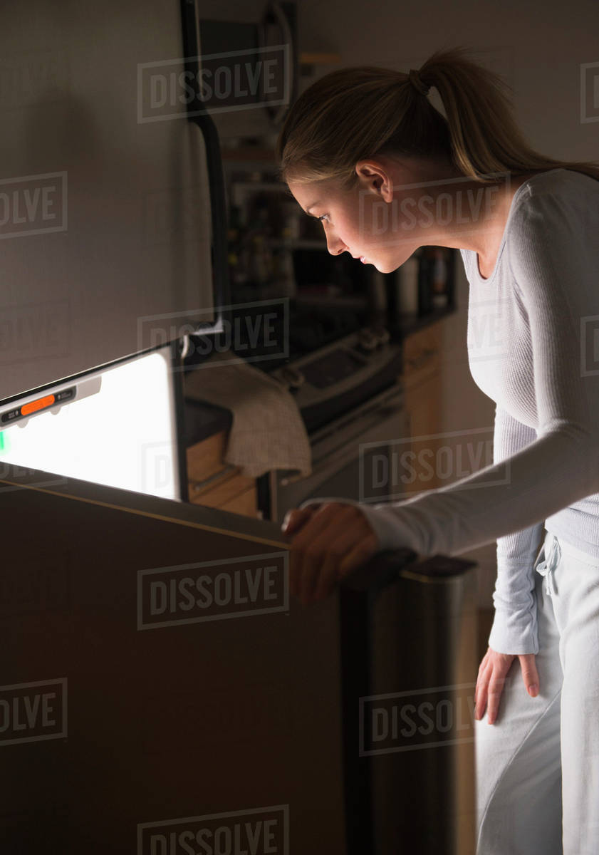 Woman opening fridge at night - Royalty-free Stock Photo | Dissolve