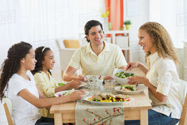 Parents with daughters (10-13) eating dinner - Stock Photo - Dissolve