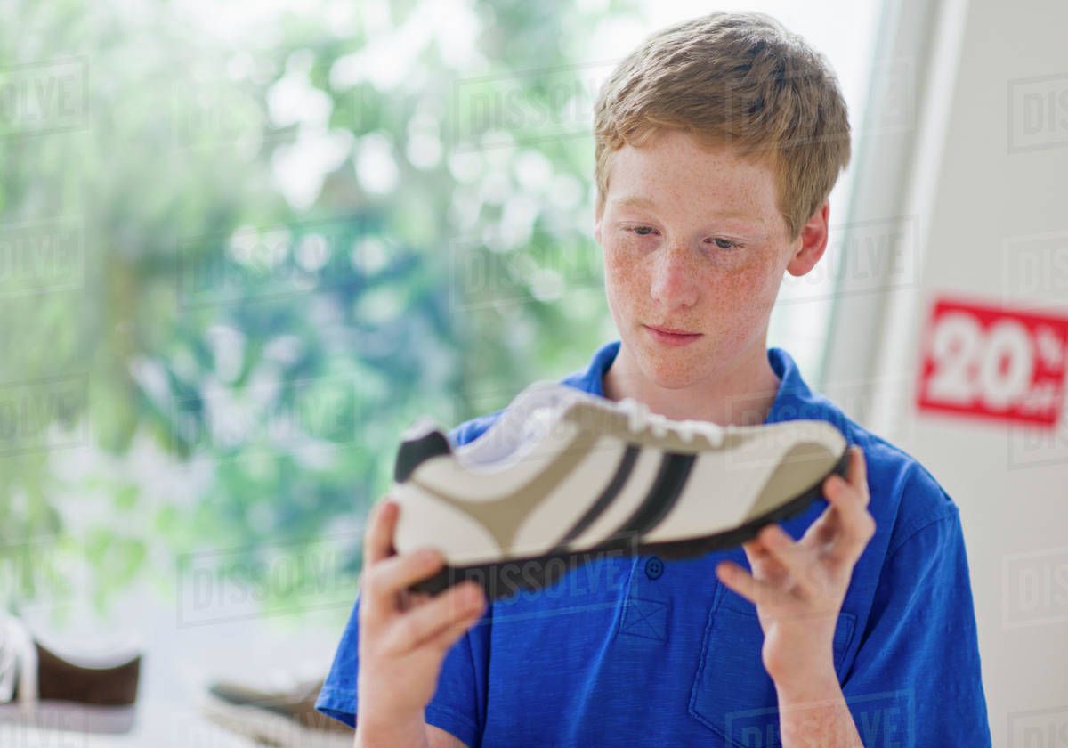 Boy (16-17) looking at shoe in shoe store - Royalty-free Stock Photo ...