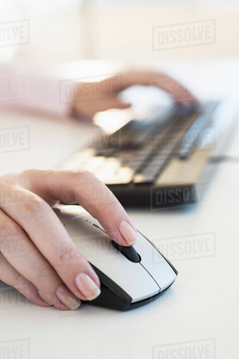 Close up of woman's hands using computer keyboard and computer mouse ...