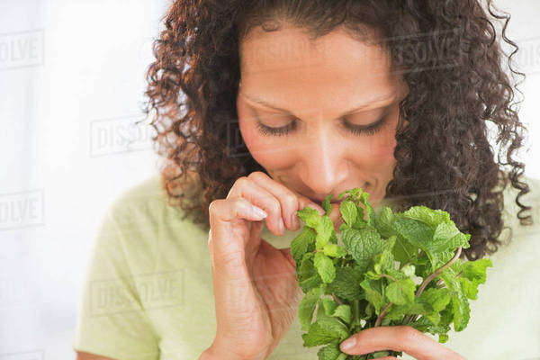 Woman smelling fresh mint - Stock Photo - Dissolve