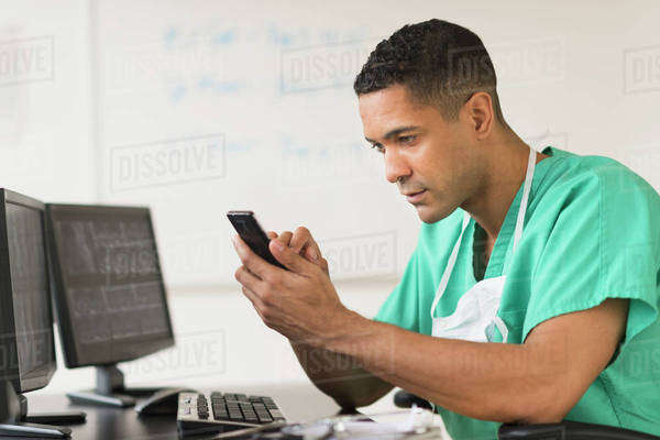 Surgeon working on computer and text messaging - Stock Photo - Dissolve