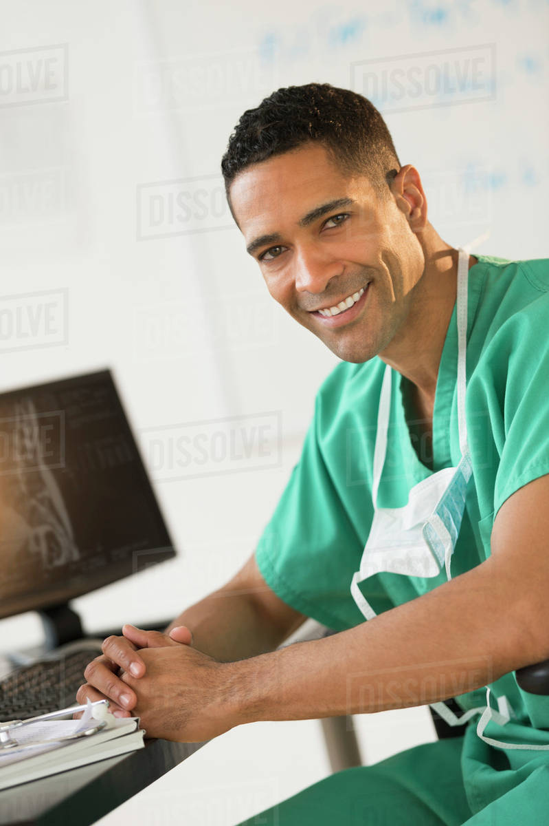 Portrait of male surgeon sitting at desk in hospital - Royalty-free ...