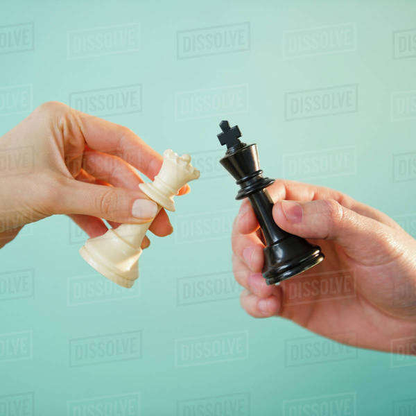 Close up of man's and woman's hands holding chess pieces, studio shot ...