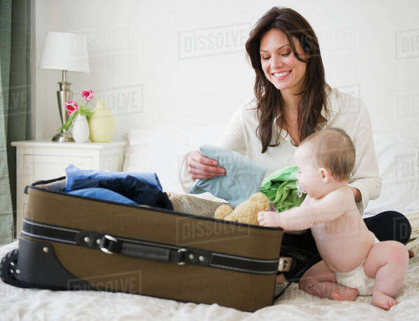 Mother with baby daughter (6-11 months) packing suitcase - Royalty-free ...
