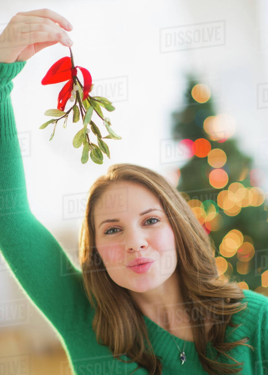 Portrait of young woman holding mistletoe stem over head - Royalty-free ...