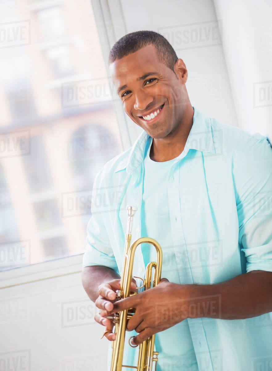 Young man holding trombone - Stock Photo - Dissolve