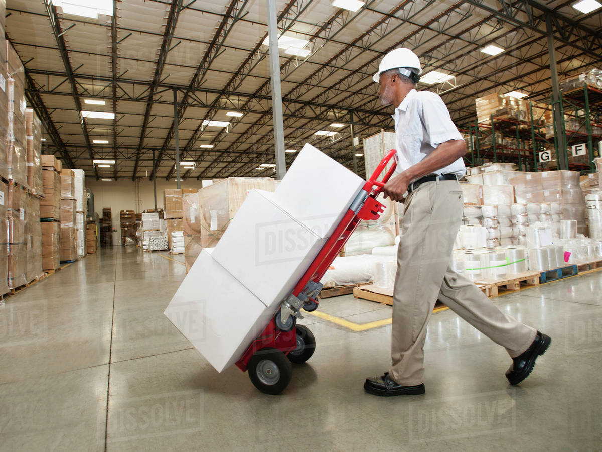 Man pushing hand truck in warehouse - Royalty-free Stock Photo | Dissolve