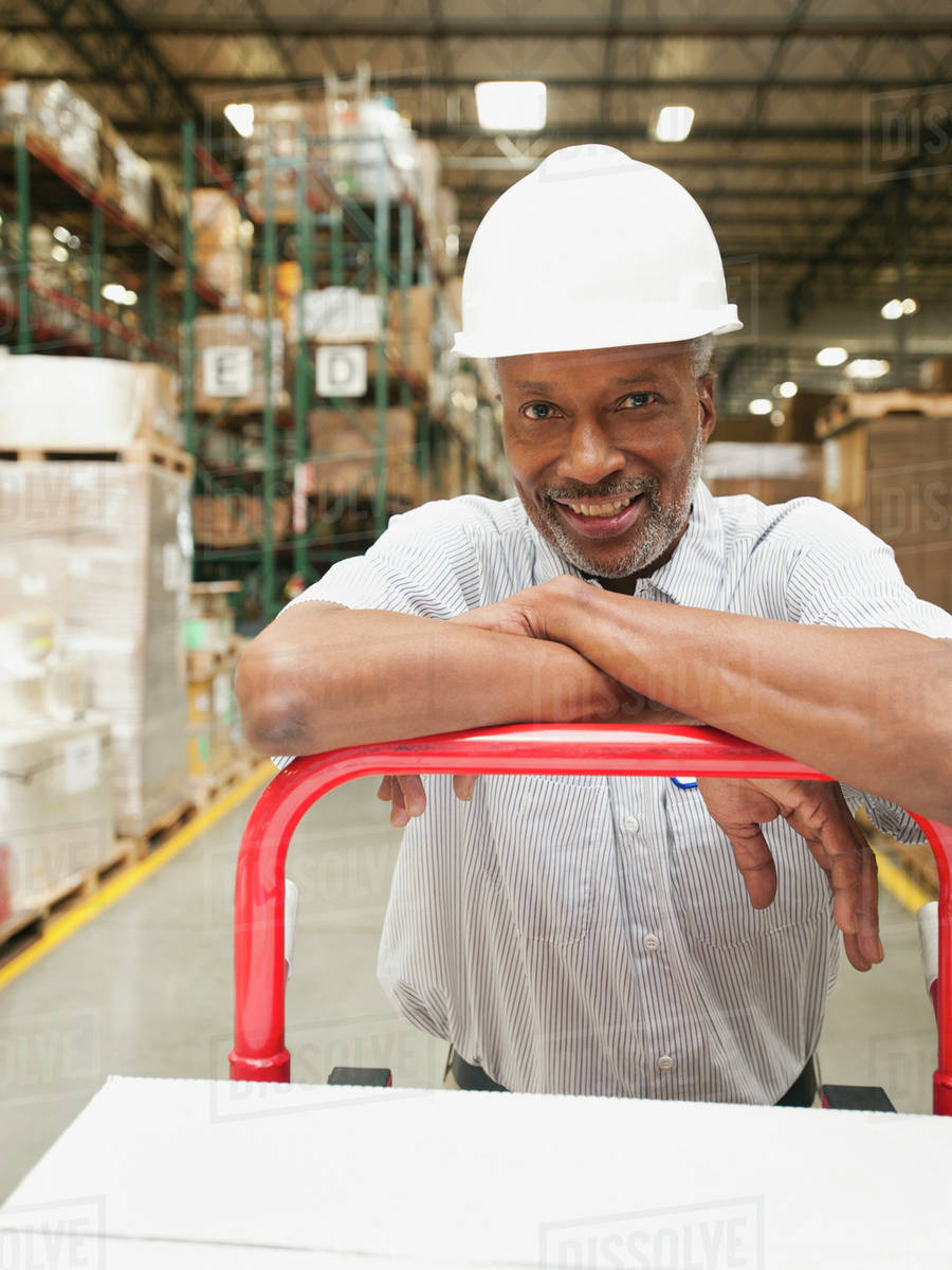 Portrait of man pushing hand truck in warehouse - Royalty-free Stock ...