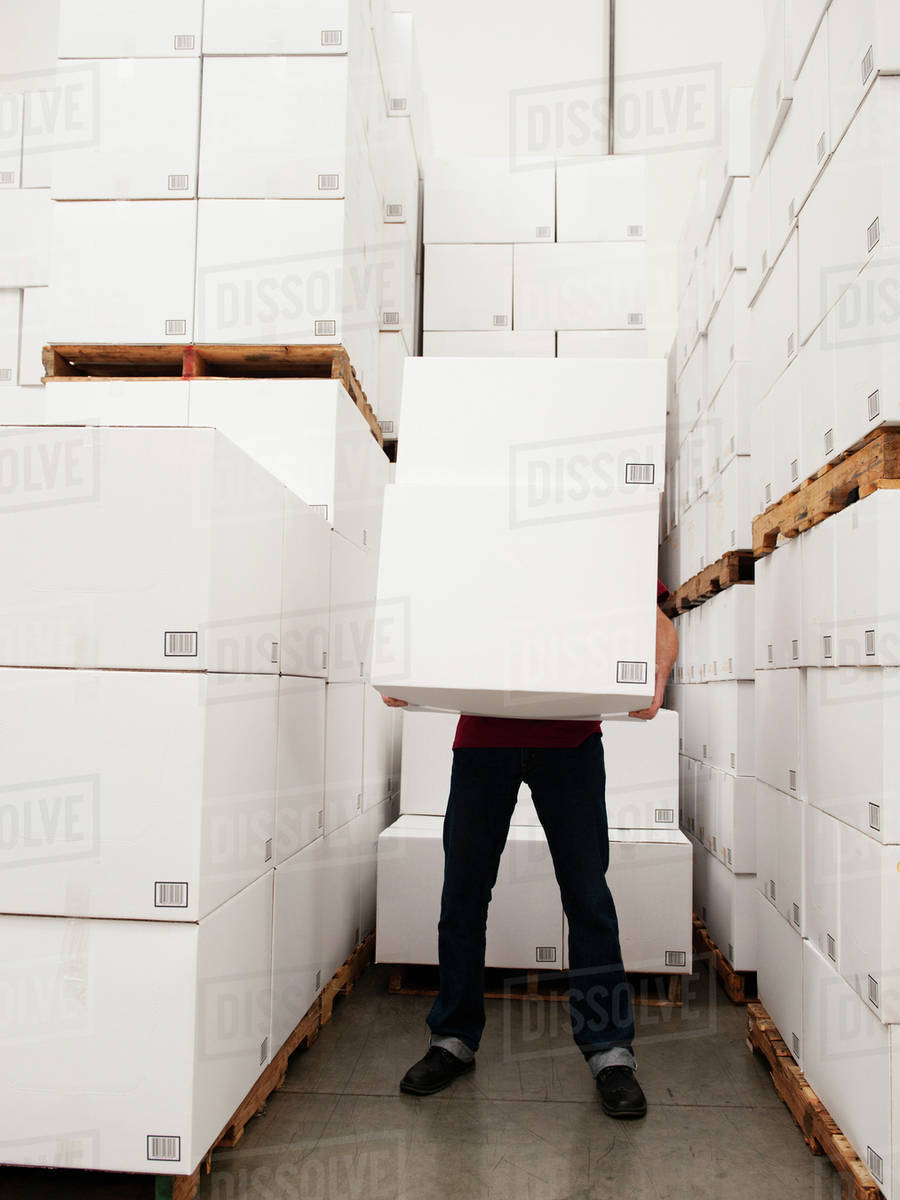 Worker carrying boxes in warehouse - Stock Photo - Dissolve