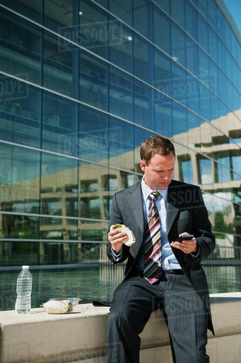 Young man taking lunch brake on ledge - Royalty-free Stock Photo | Dissolve