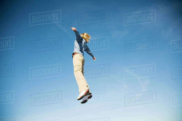 Woman in floating in blue sky with arms outstretched - Stock Photo ...