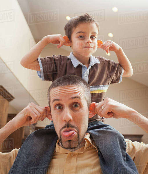 Father and son (6-7) pulling funny faces - Stock Photo - Dissolve