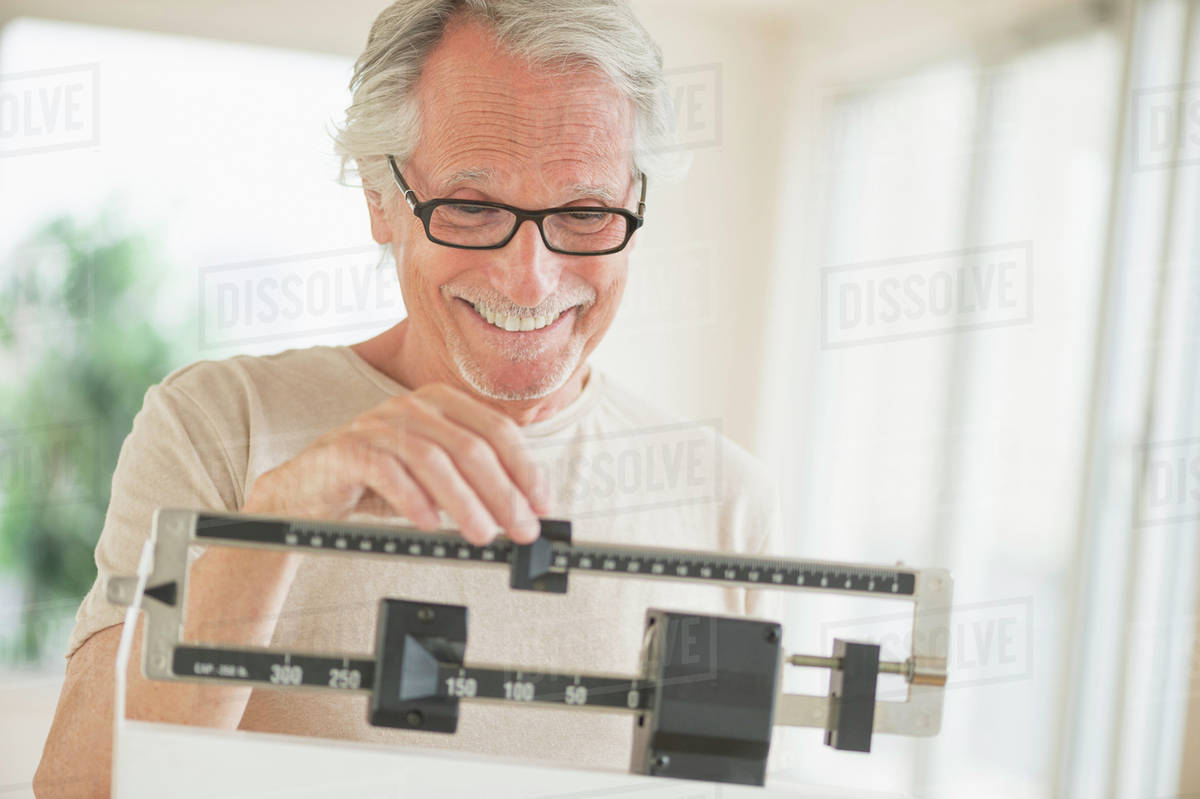 Senior man on weight scale - Stock Photo - Dissolve