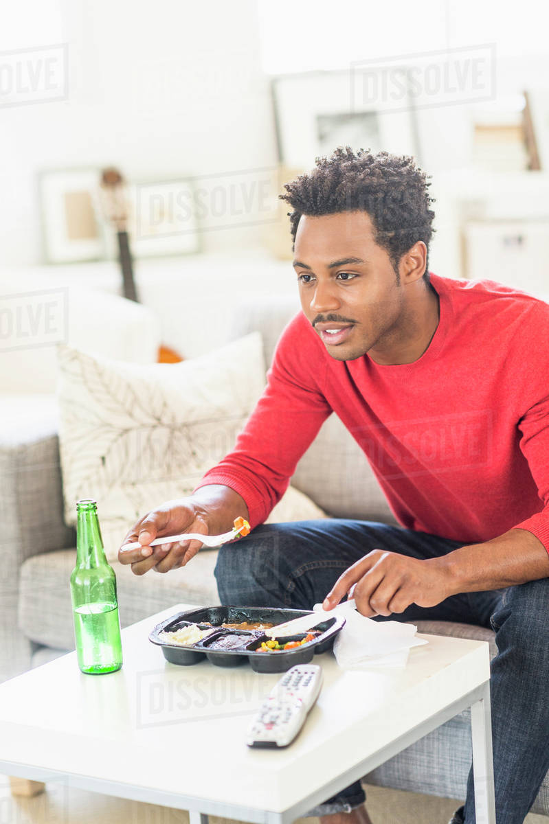 Man eating dinner and watching television - Stock Photo - Dissolve
