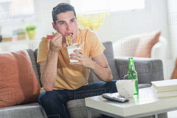 Man eating take out meal and watching television - Stock Photo - Dissolve