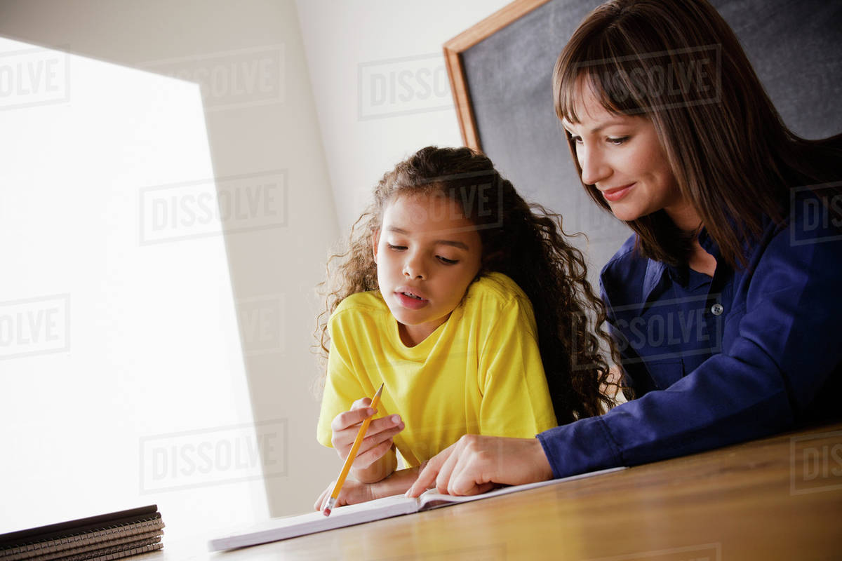 Schoolgirl writing with teacher in classroom - Royalty-free Stock Photo ...