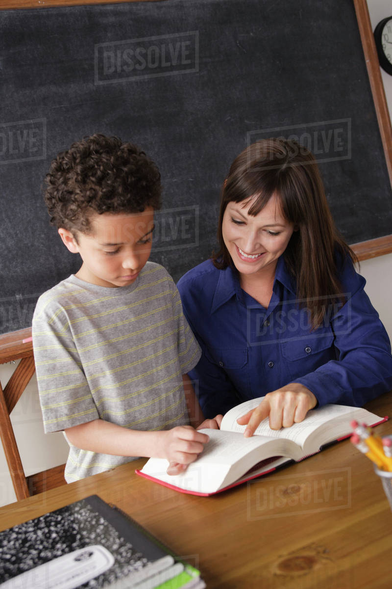 Schoolboy reading with teacher in classroom - Royalty-free Stock Photo ...