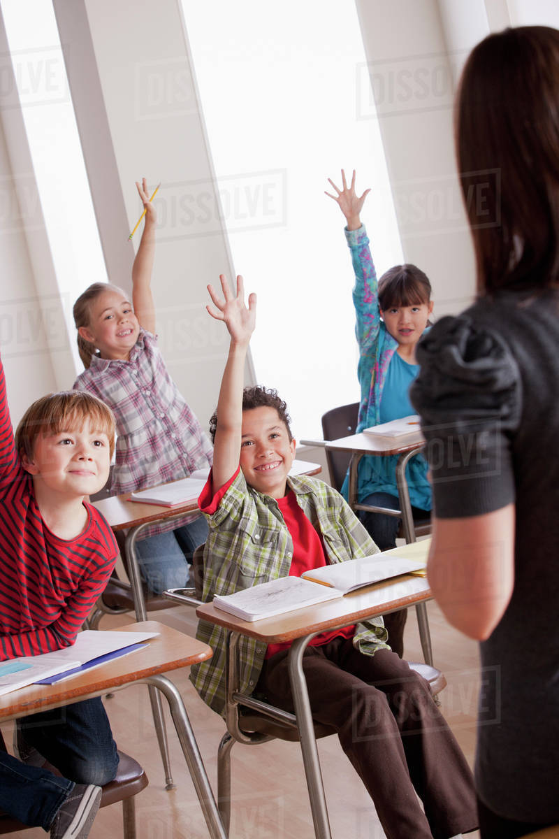 Pupils in classroom raising hands - Royalty-free Stock Photo | Dissolve