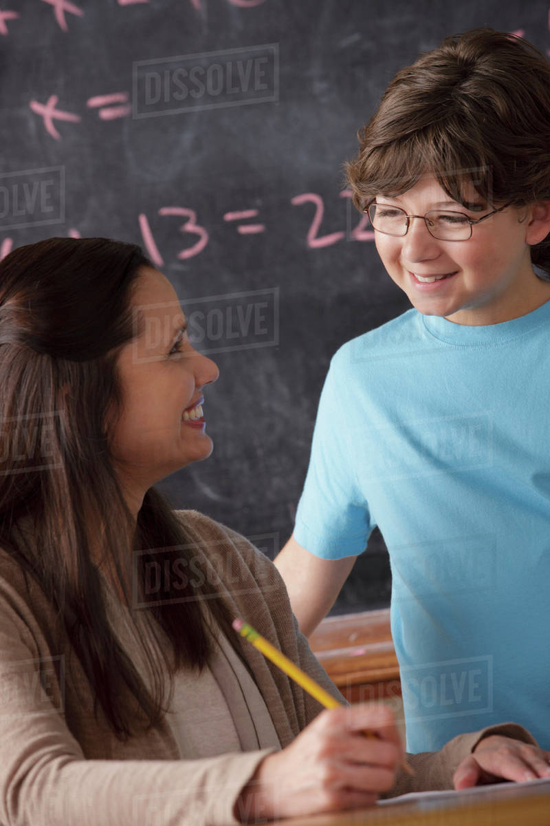 Schoolboy (10-11) and teacher face to face with blackboard in ...