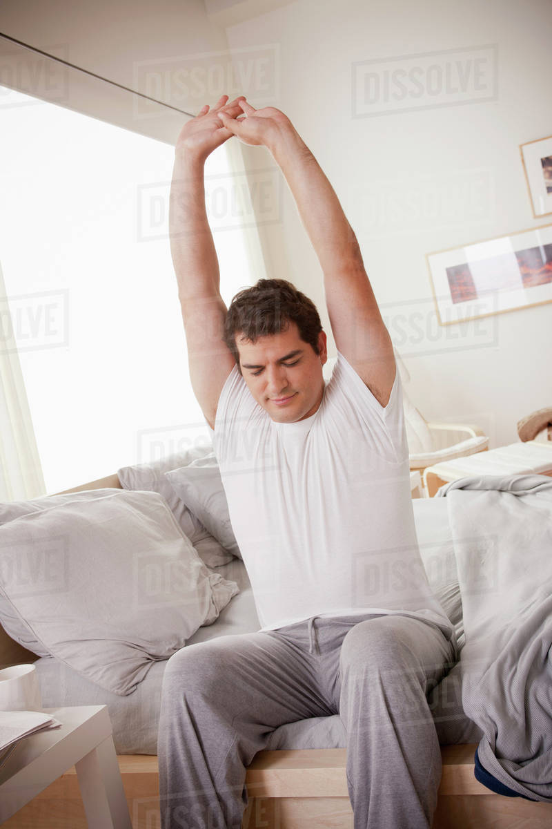 Young man stretching after waking up - Royalty-free Stock Photo | Dissolve