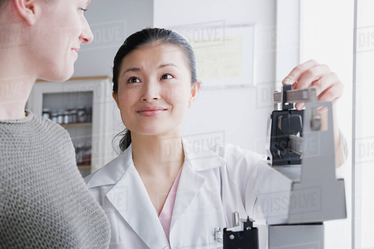 Close up of female doctor measuring woman's weight - Stock Photo - Dissolve