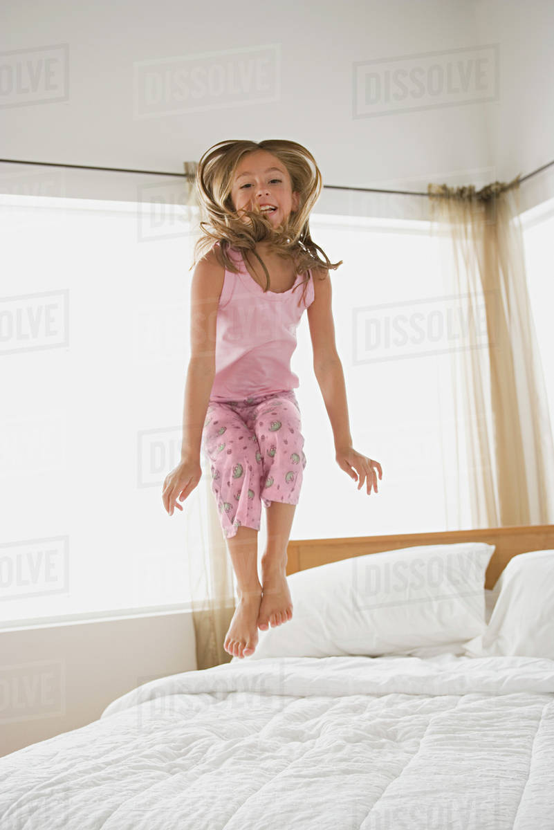 Girl jumping on bed - Royalty-free Stock Photo | Dissolve