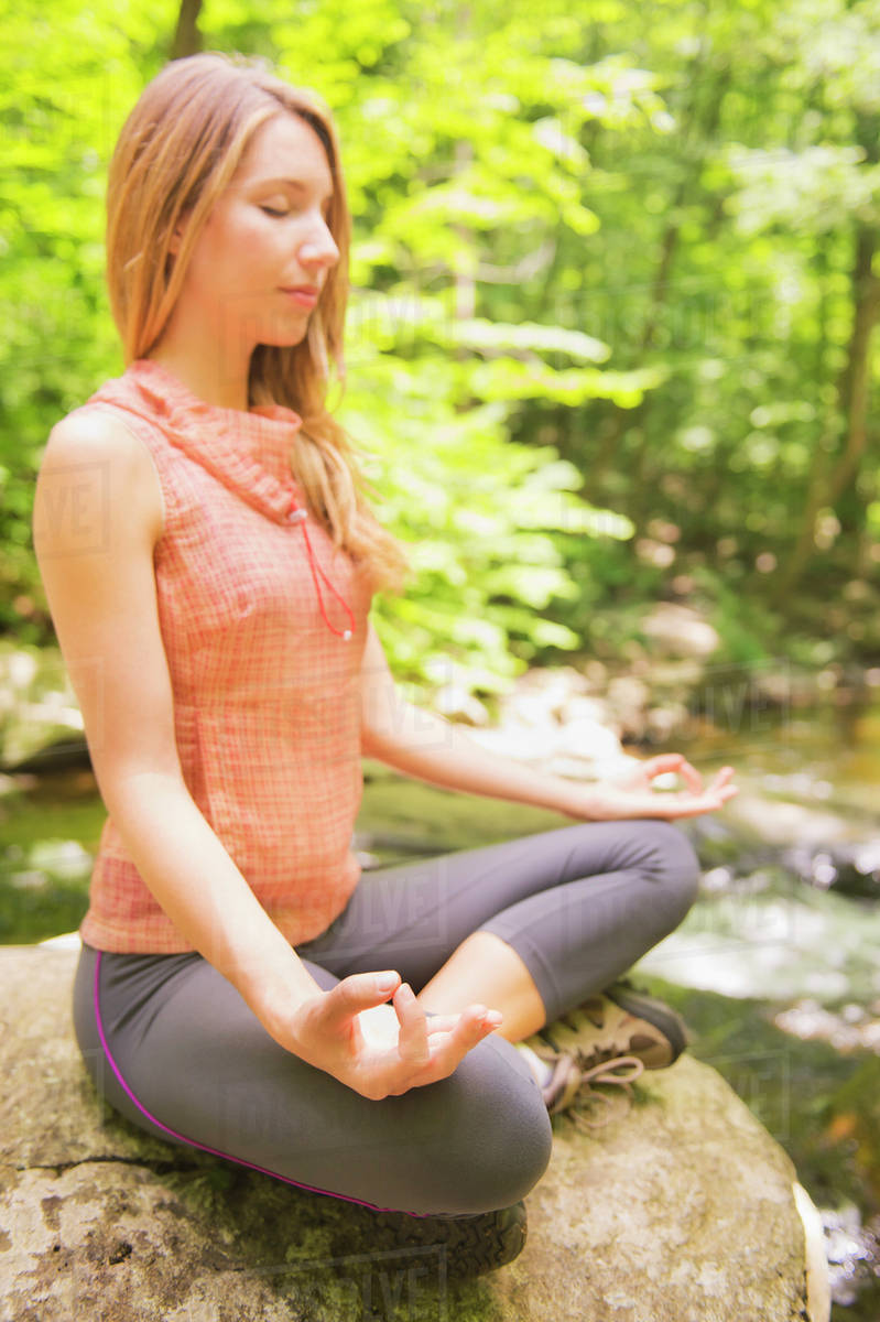Woman practicing joga in forest - Stock Photo - Dissolve