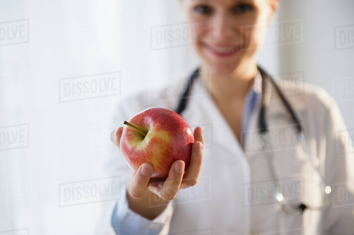 Portrait of doctor giving apple - Royalty-free Stock Photo | Dissolve