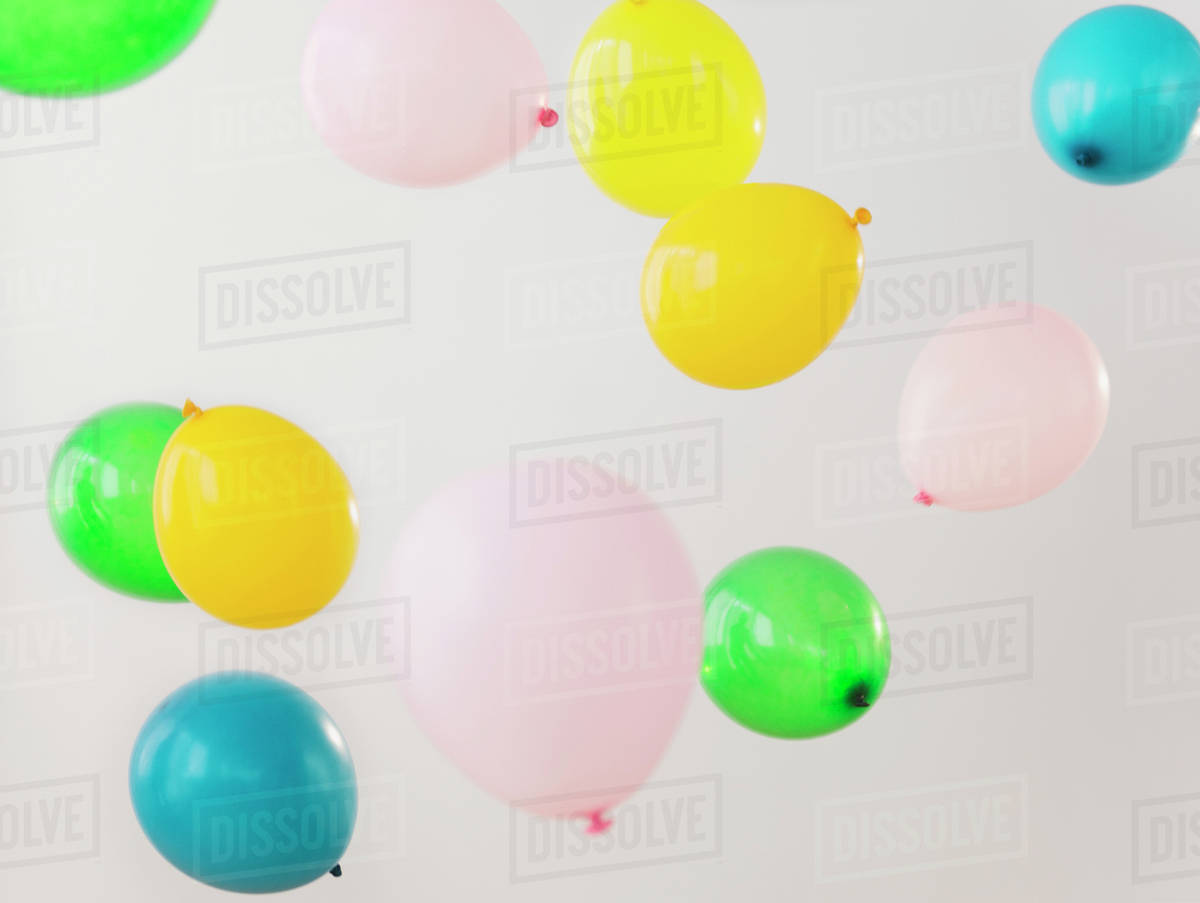 Studio Shot of colorful balloons falling down - Stock Photo - Dissolve